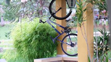 Uma bicicleta pendurada em uma viga de madeira sob uma pérgola.