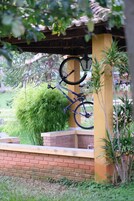 Uma bicicleta pendurada em uma viga de madeira sob uma pérgola.