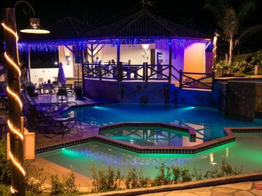 Uma área de piscina com um espaço de estar coberto, uma piscina pequena e uma parede de pedra.