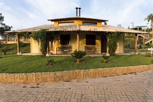Uma casa de dois andares com telhado de telhas, varanda coberta e gramado bem cuidado.