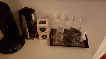 Cantinho de café e chá com cafeteira, caixa de chá, copos e xícaras.