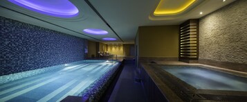 Uma área de spa moderna com uma piscina grande, espaço para sentar e uma banheira de hidromassagem separada.