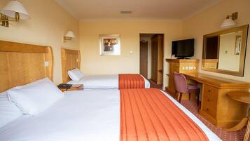 Quarto de hotel com duas camas, uma escrivaninha, uma cadeira, uma televisão e um espelho.