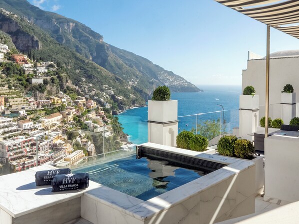 Piscina no terraço com vista para o mar e uma cidade costeira.
