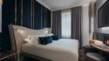 Quarto de hotel moderno com uma cama grande, uma escrivaninha e uma televisão.