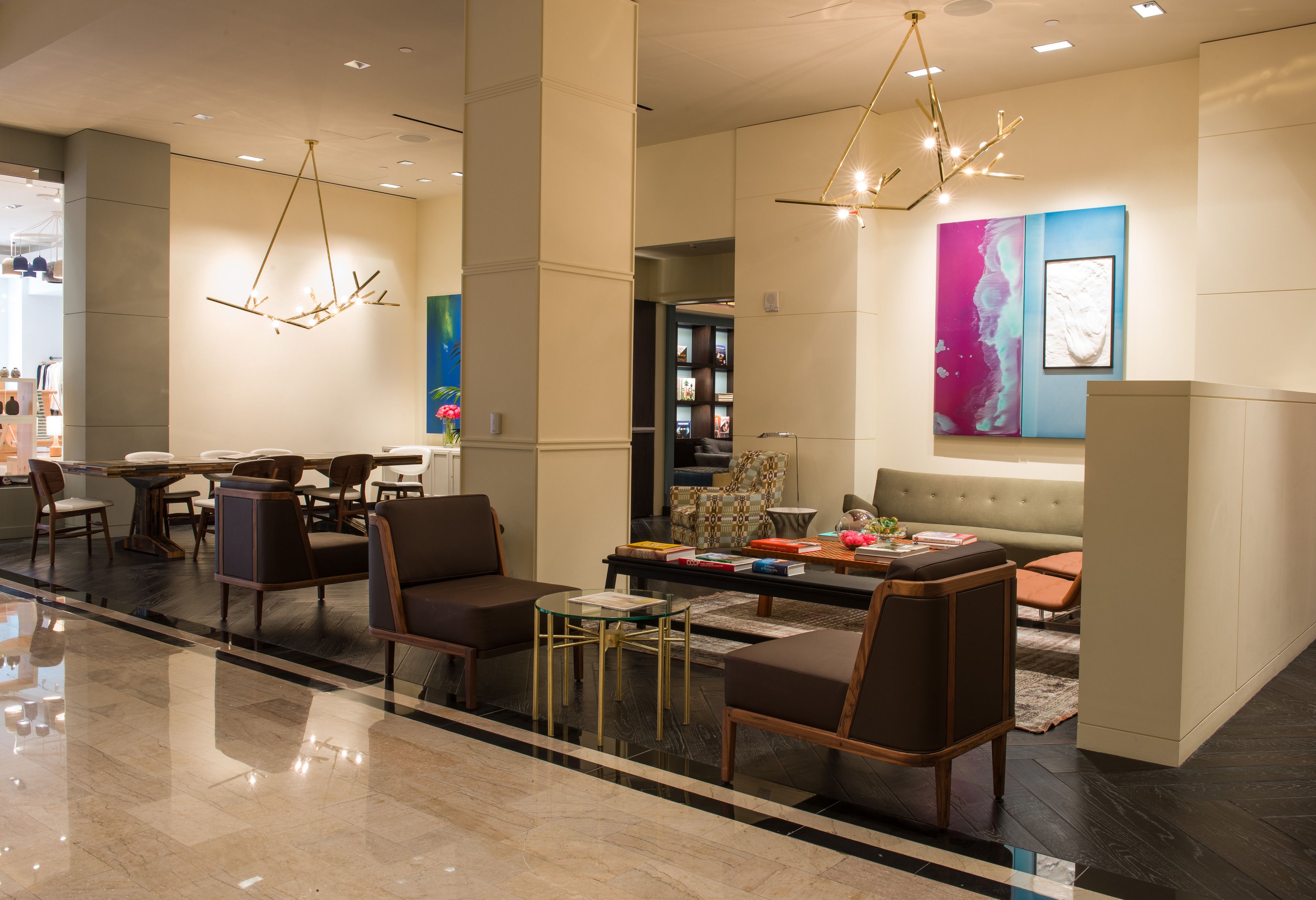 Um lobby moderno com área de estar, mesa de centro e estante de livros.