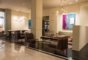 Um lobby moderno com área de estar, mesa de centro e estante de livros.