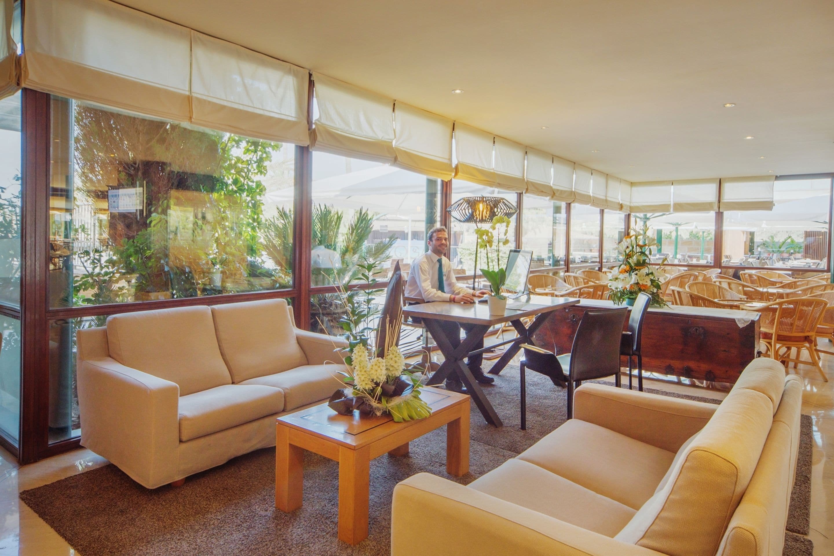 Um espaço amplo e interno, com grandes janelas, um sofá, uma mesa de jantar e cadeiras.