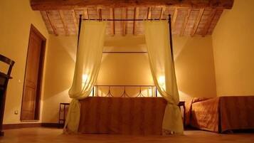 Um quarto com teto de madeira, uma cama com cabeceira e uma janela com cortinas.