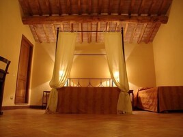 Um quarto com teto de madeira, uma cama com cabeceira e uma janela com cortinas.