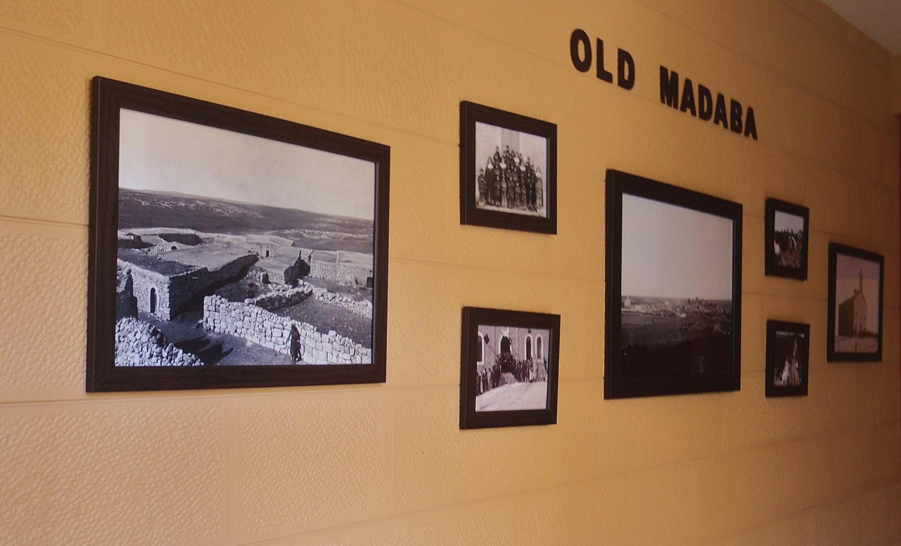 Paredes decoradas com várias fotografias emolduradas, incluindo uma grande de um local histórico e outras menores de paisagens e edifícios.