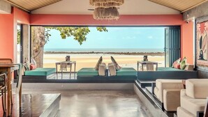 Quarto à beira-mar com vista para o oceano, luminária pendente e áreas de estar.