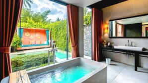 Casa de banho moderna com banheira, pia e uma grande janela com vista para uma piscina e vegetação exuberante.