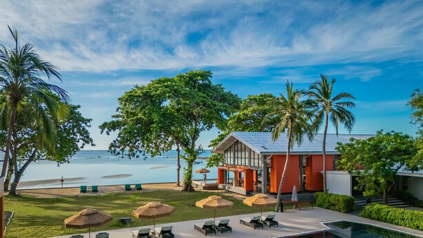 Um resort com piscina, espreguiçadeiras e vista para o oceano.