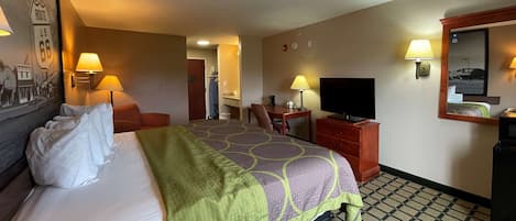 Quarto de hotel com cama, duas luminárias de cabeceira, uma escrivaninha com cadeira, televisão e um espelho.