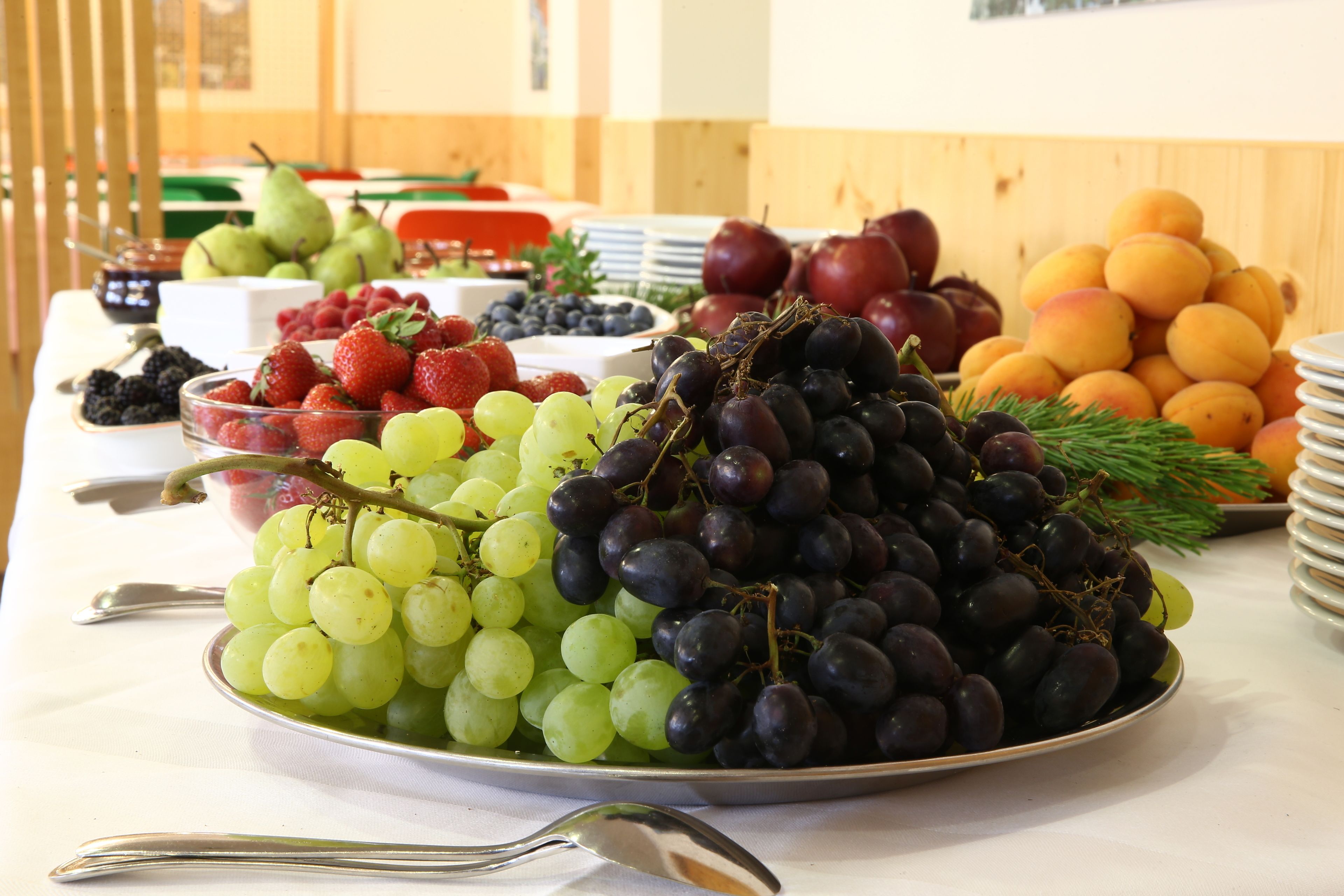 Uma mesa com diversas frutas, incluindo uvas, morangos, peras e pêssegos.