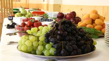 Uma mesa com diversas frutas, incluindo uvas, morangos, peras e pêssegos.