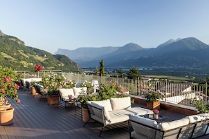 Terraço no telhado com área de estar ao ar livre, plantas em vasos e vista panorâmica das montanhas.