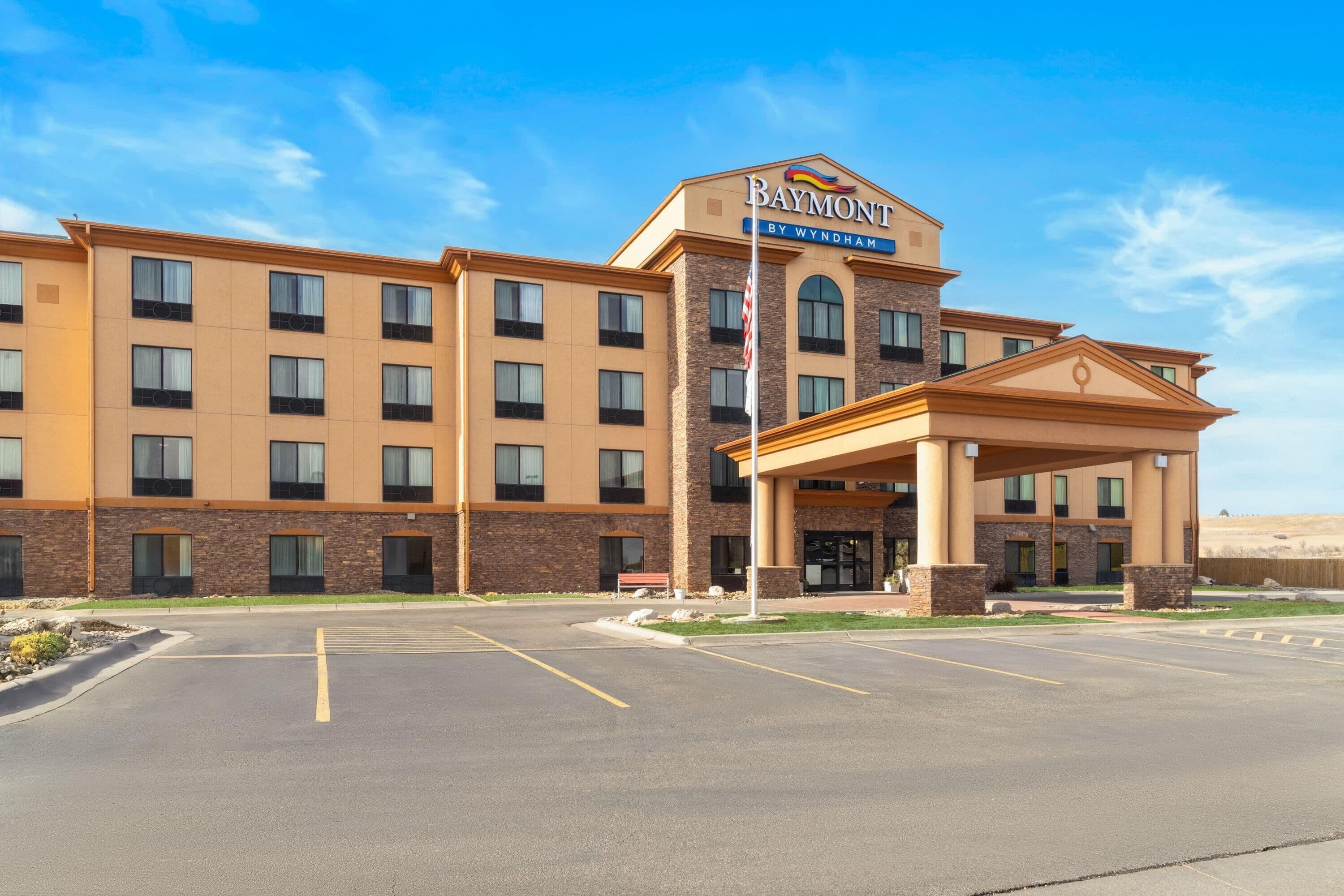Um hotel Baymont by Wyndham com fachada moderna, entrada coberta e estacionamento.