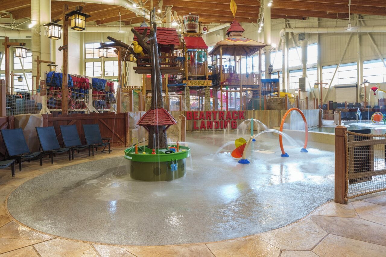 Espaço de recreação infantil com fonte, assentos e estrutura de escalada.