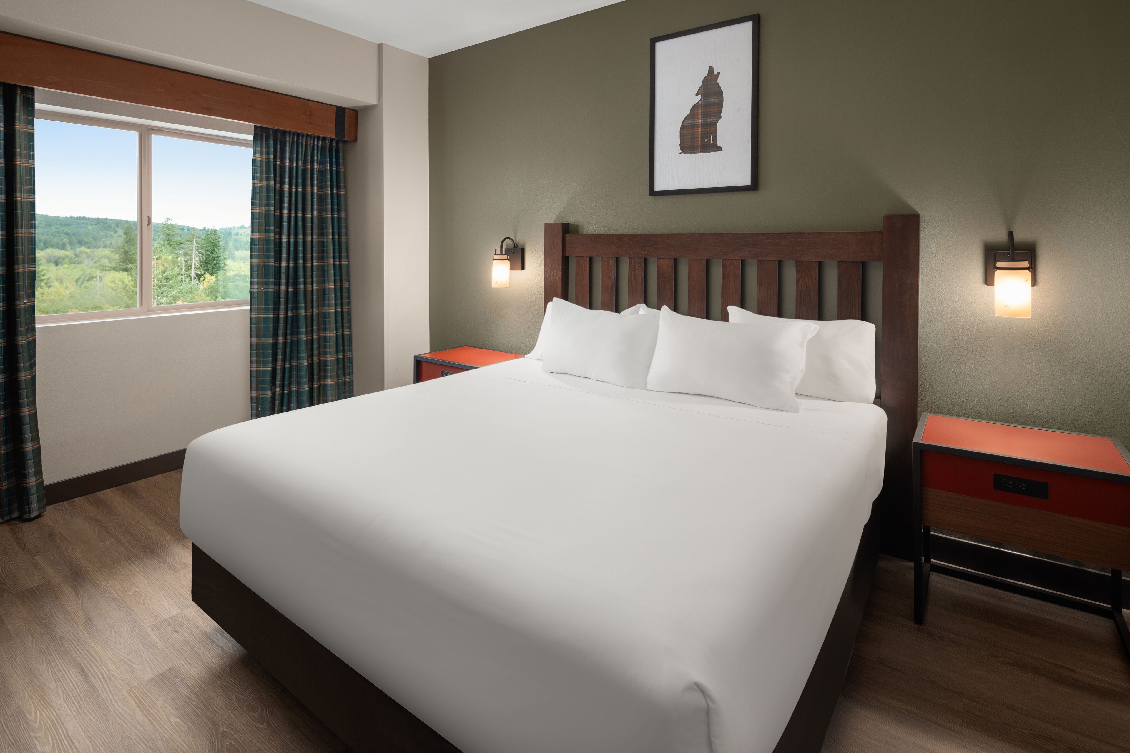 Quarto de hotel bem arrumado com uma cama grande, duas mesas de cabeceira, um quadro na parede e uma janela com cortinas.