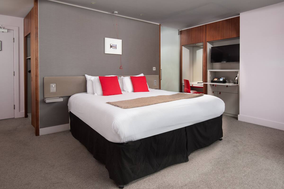 Quarto moderno com uma cama grande, televisão e guarda-roupa.