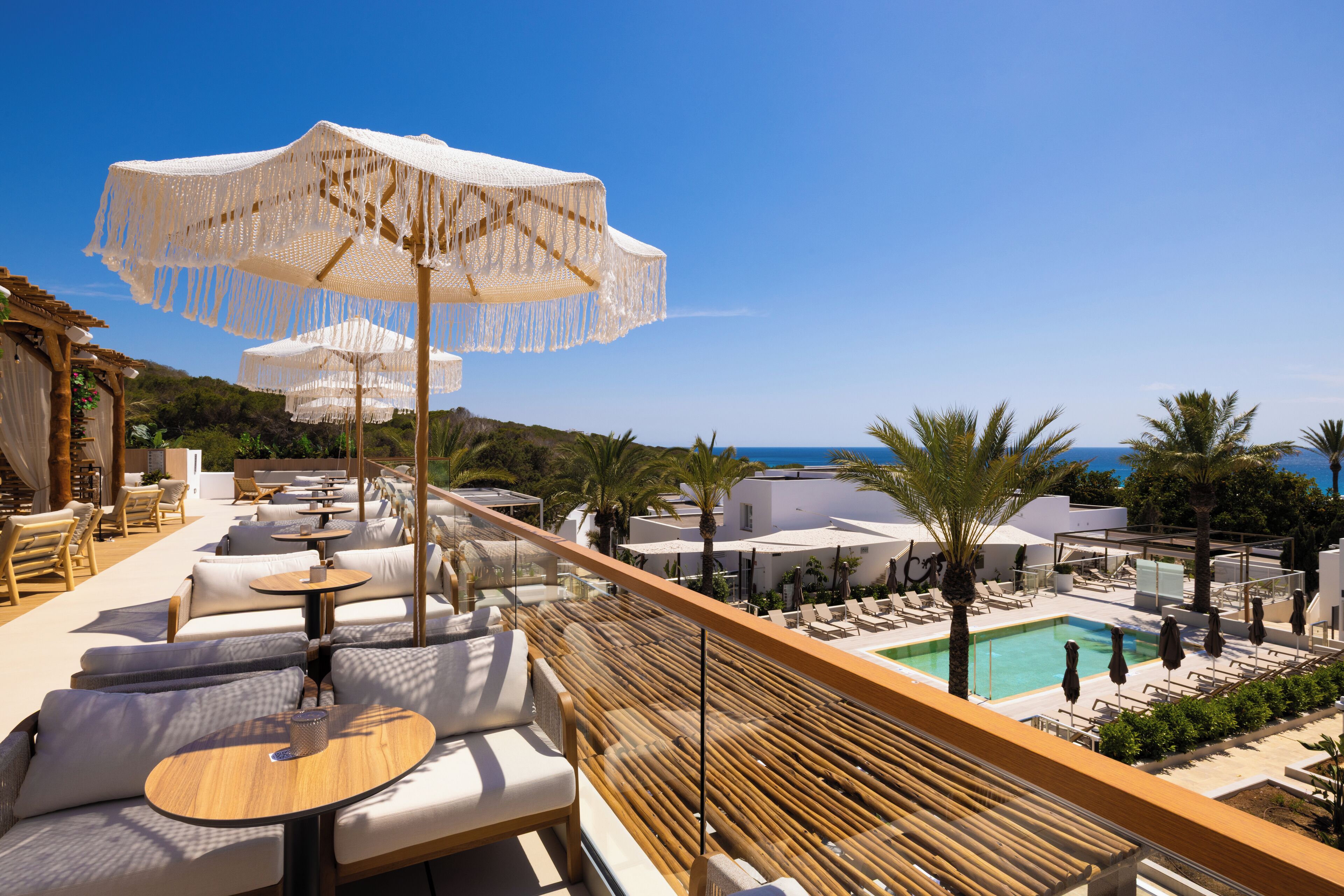 Terraço no telhado com área de estar externa, guarda-sóis e piscina.