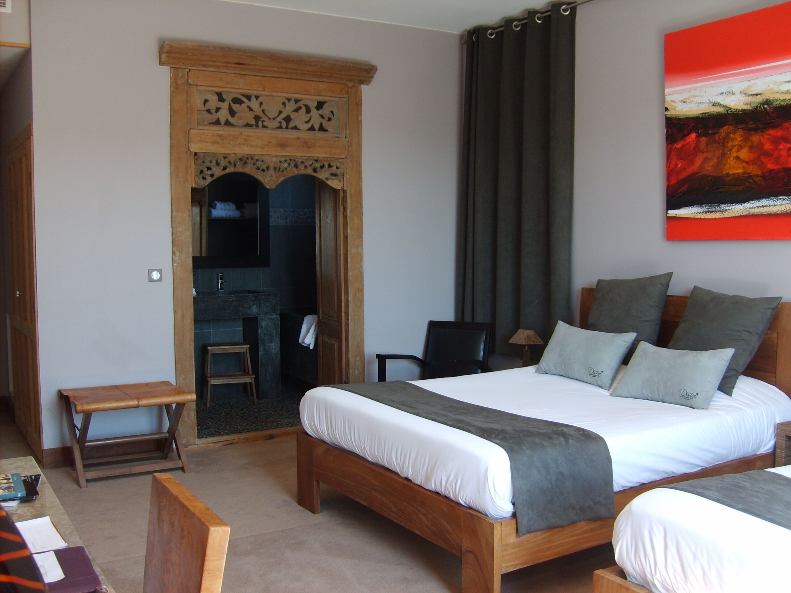 Quarto de hotel com uma cama grande, uma escrivaninha e uma cadeira.