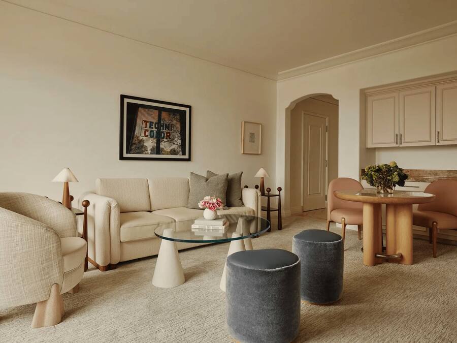 Uma sala de estar com sofá, poltronas, mesa de centro e um espaço de jantar com mesa e cadeiras.