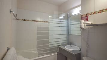 Casa de banho com cabine de duche em vidro, lavatório e sanita.
