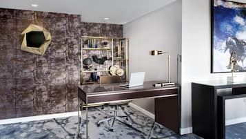 Espaço de escritório moderno com escrivaninha, cadeira, estante e um quadro na parede.