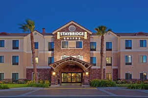 Um hotel Staybridge Suites com fachada de tijolos, várias janelas e entrada central.