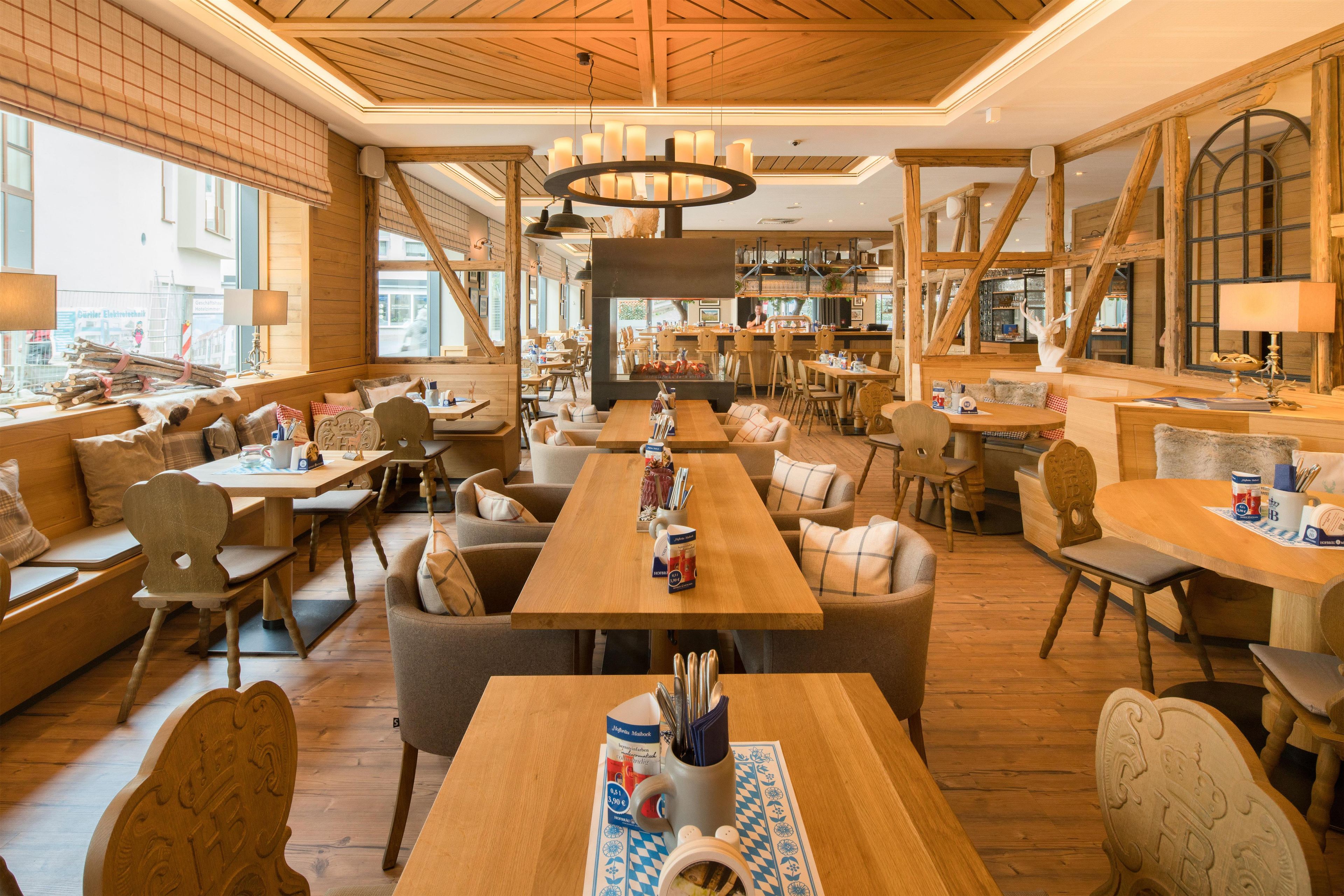 Um restaurante amplo com tetos de madeira altos, várias mesas de jantar e assentos confortáveis.