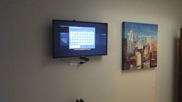 Uma televisão fixada na parede exibindo a tela de conexão Wi-Fi para hóspedes.