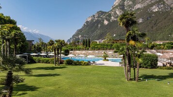Resort com piscina, palmeiras e vista para montanhas.
