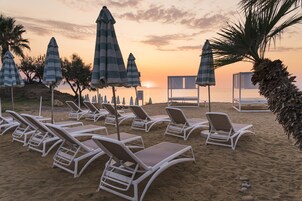 Na praia, espreguiçadeiras, guarda-sóis, prática de vôlei de praia