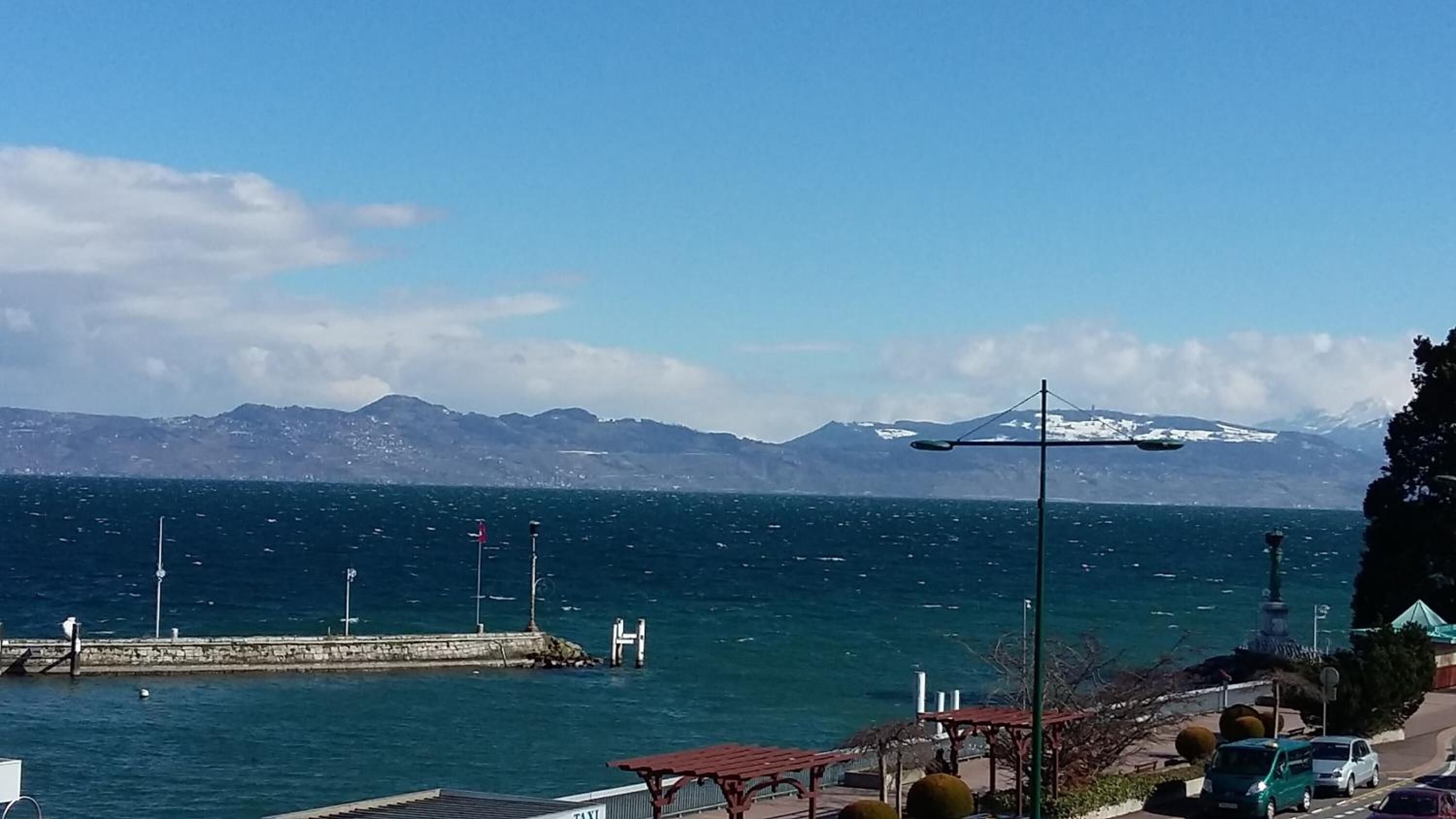 Vista costeira com um cais, uma cordilheira e céu limpo.