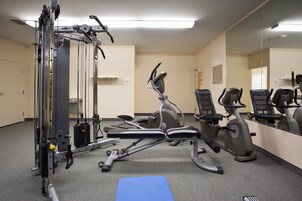 Uma academia com equipamentos de ginástica, um colchonete azul e um espelho na parede.