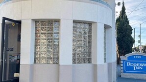 Edifício em esquina com janela de blocos de vidro, placa da Rodeway Inn e um poste de luz.