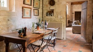 Uma área de refeições rústica com uma mesa de madeira, cadeiras e piso de azulejos.