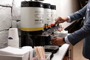 Máquina de café com etiqueta indicando '100% Grãos Arábica' e 'Origem: América Central e América do Sul'.