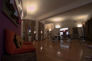 Uma sala de estar ampla com piso de madeira, um sofá e um espaço para ginástica com halteres e equipamentos de exercício.