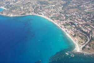 Vista aérea de uma cidade costeira com praia, áreas residenciais e uma variedade de edifícios.
