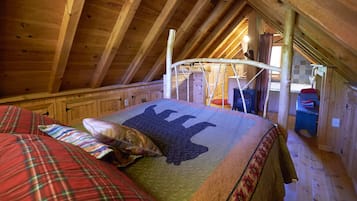 Um quarto de sótão acolhedor, com teto de madeira, uma cama com colcha estampada e uma janela com cortinas.