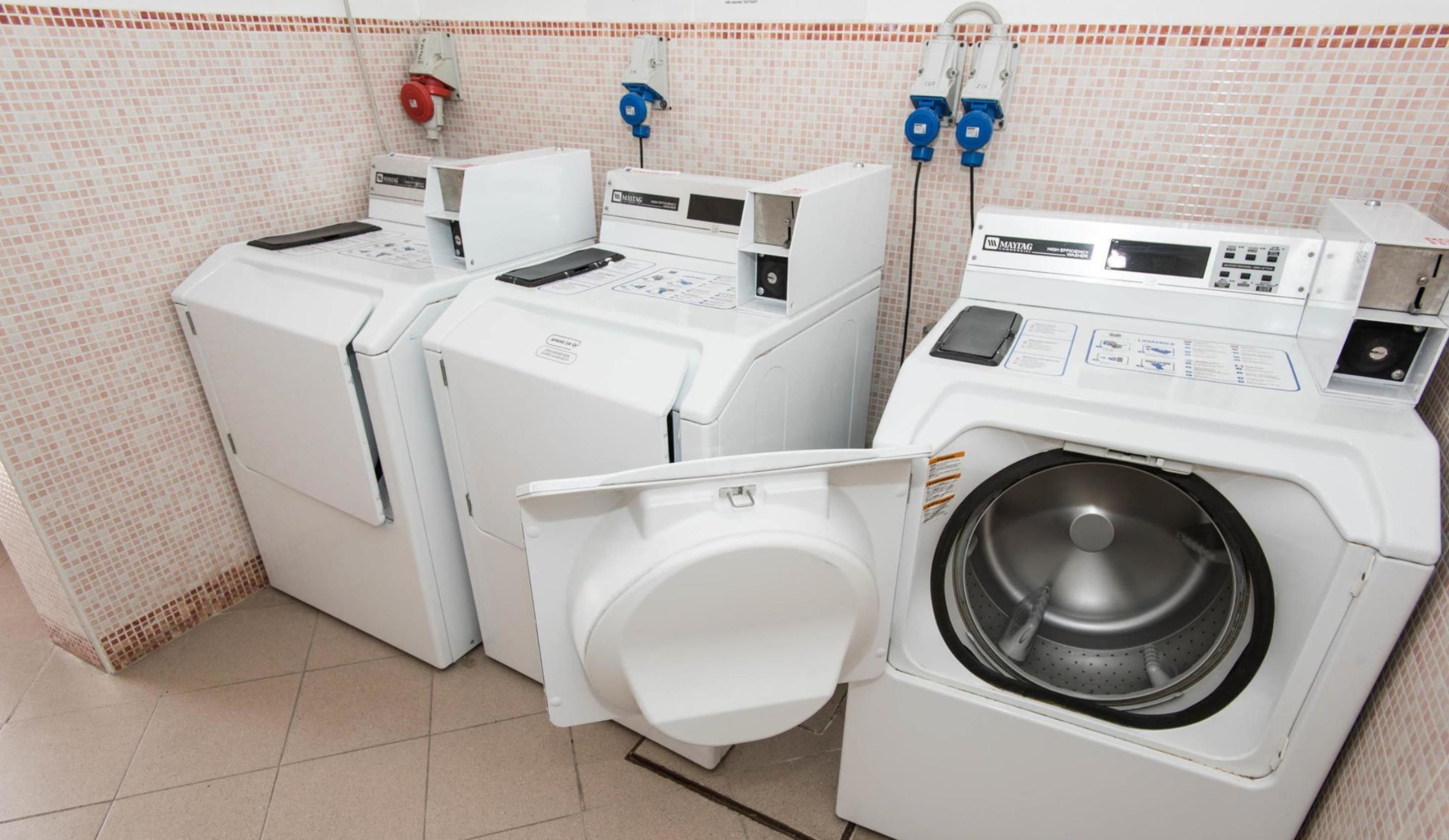 Uma lavanderia com três máquinas de lavar e uma secadora.