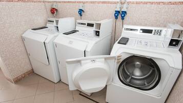 Uma lavanderia com três máquinas de lavar e uma secadora.