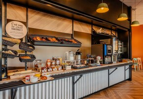 Buffet de café da manhã com pães, doces e bebidas.