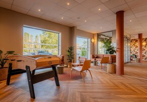 Um hall amplo com mesa de bilhar, assentos confortáveis, janelas grandes e um design de interiores moderno.
