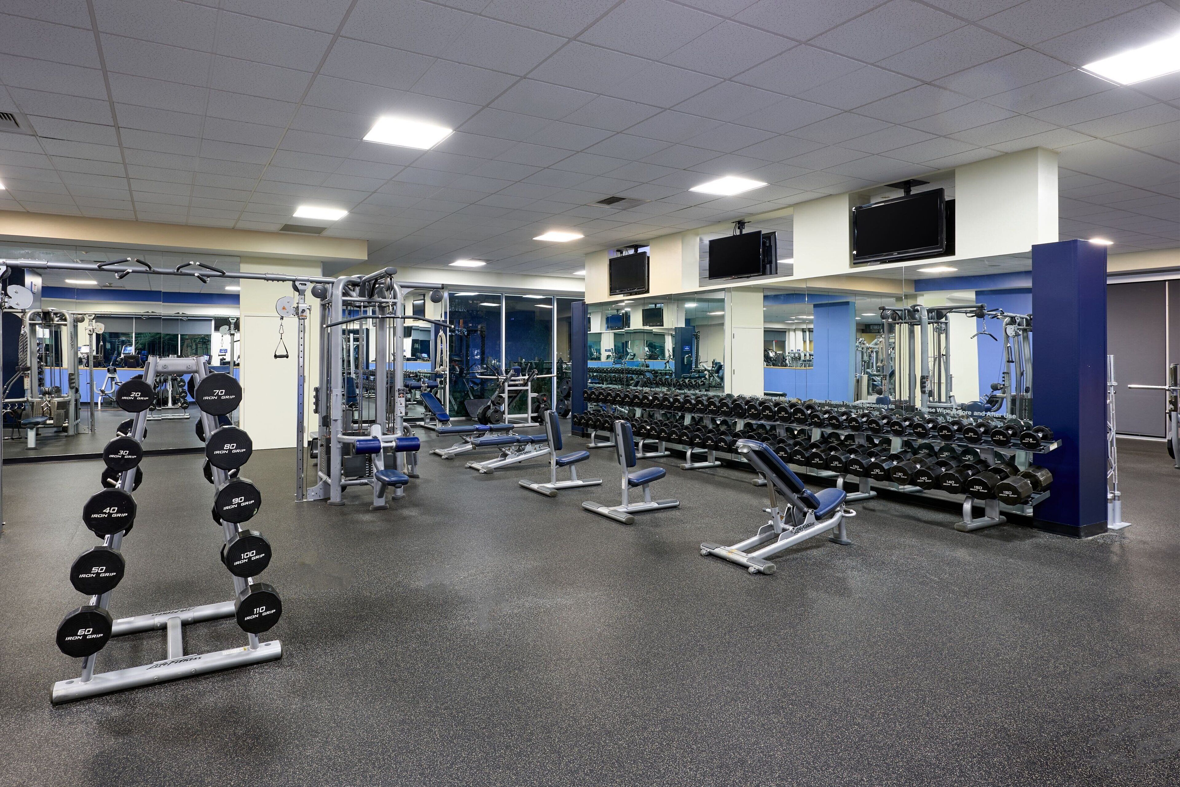 Uma academia com diversos equipamentos de exercícios, espelhos e suportes para pesos.