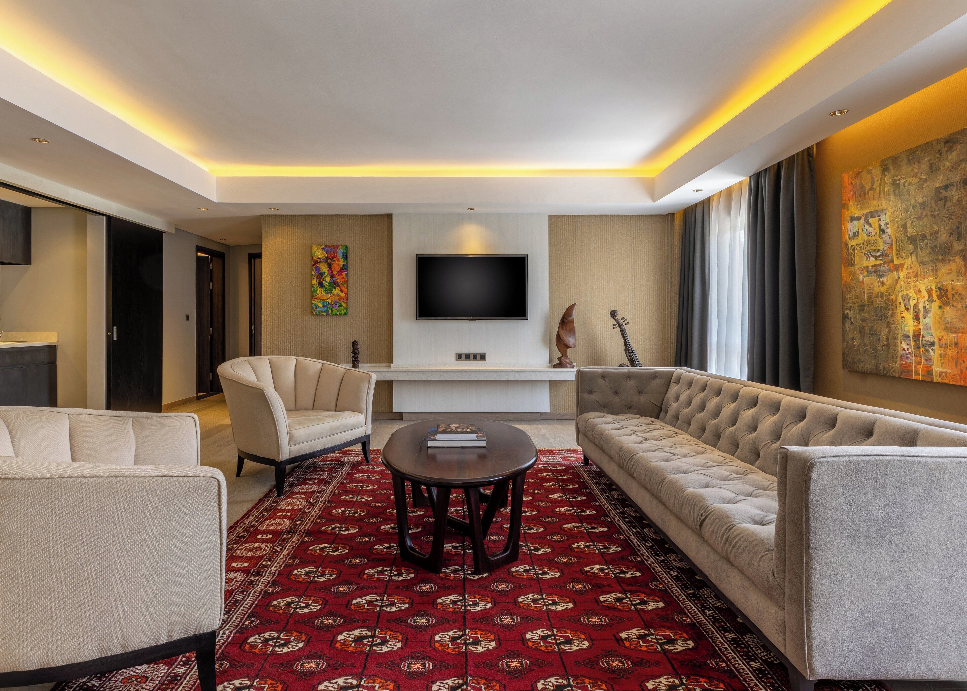 Uma sala de estar moderna com um sofá, poltronas, uma mesa de centro e uma televisão de tela plana presa à parede.